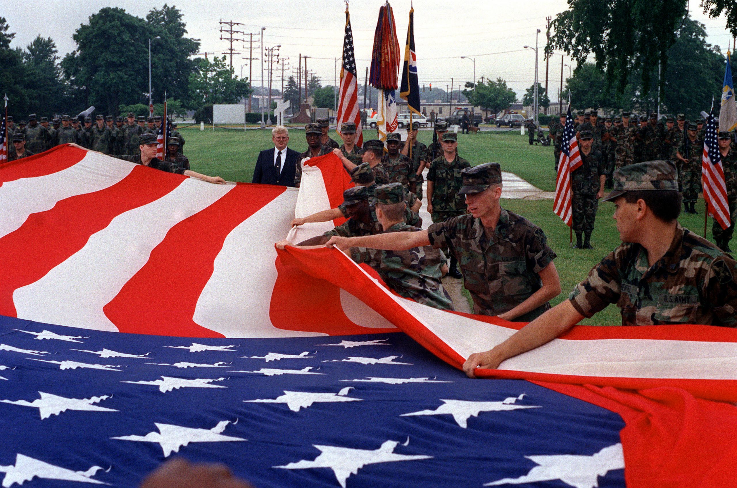 Soldiers fold an oversize American flag during the fort’s Flag Day ...